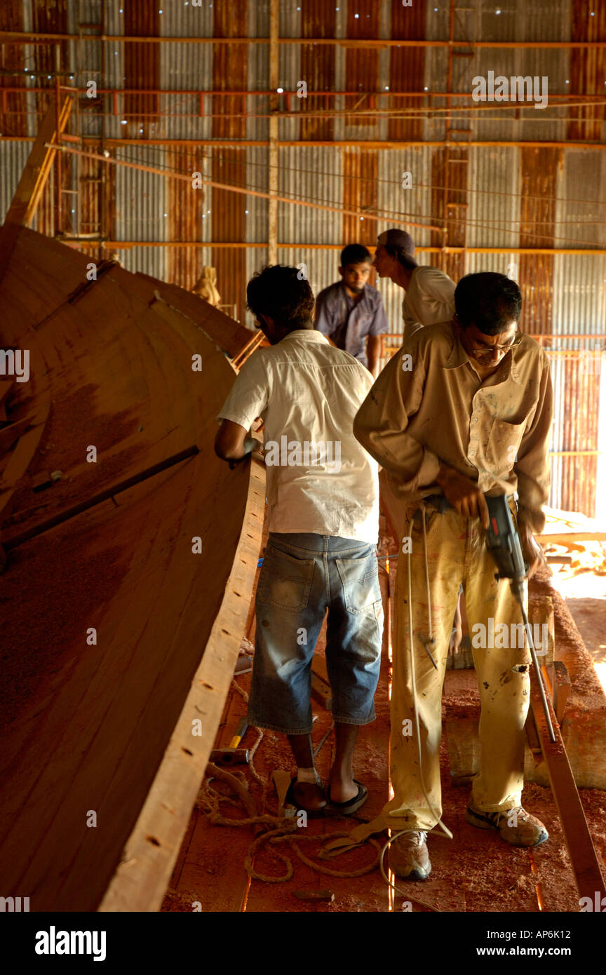 Boat builders working on the hull of a new boat at a boatyard on ...