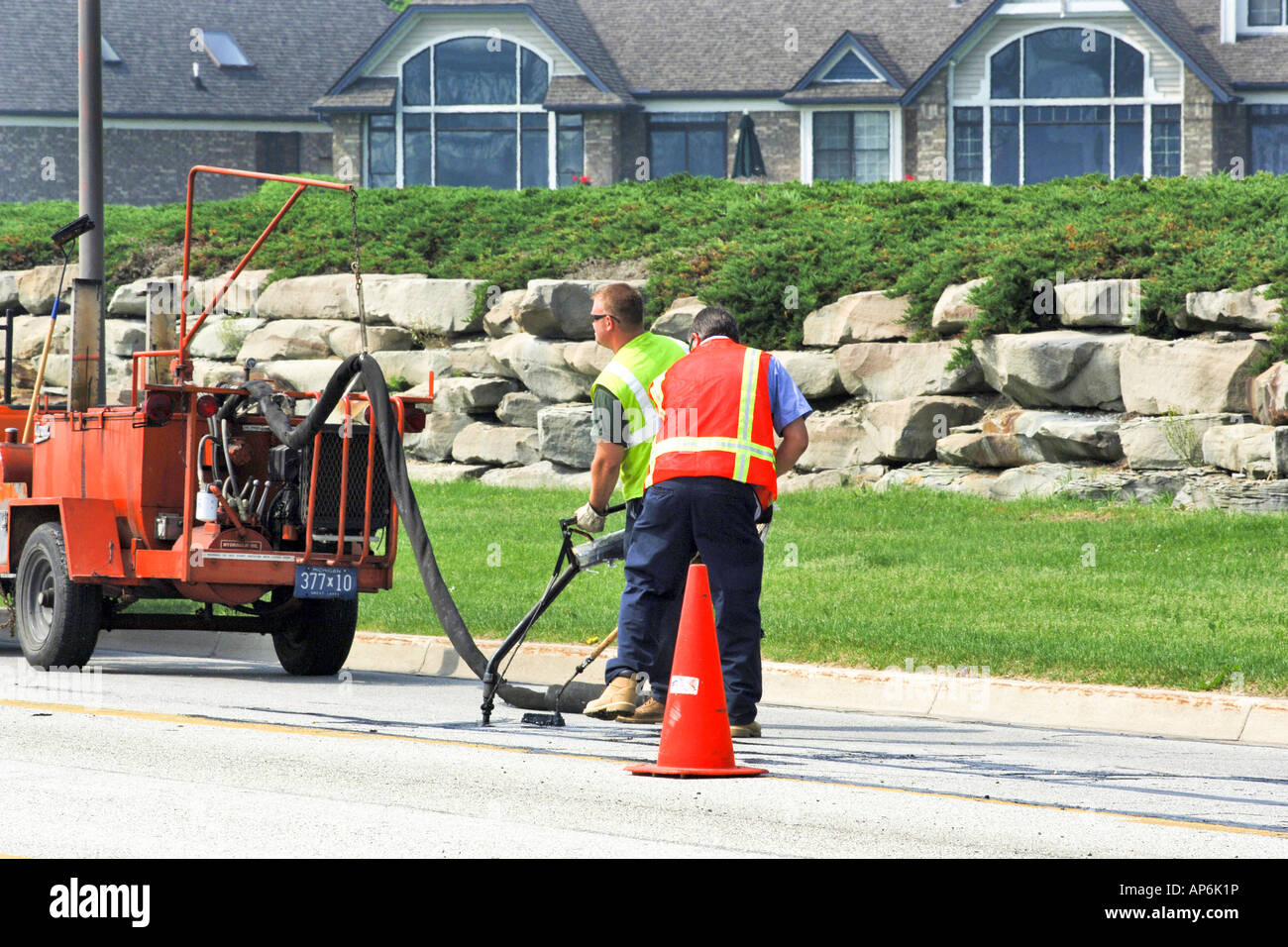 Road maintenance workers tarring in the cracked pavement Stock Photo ...