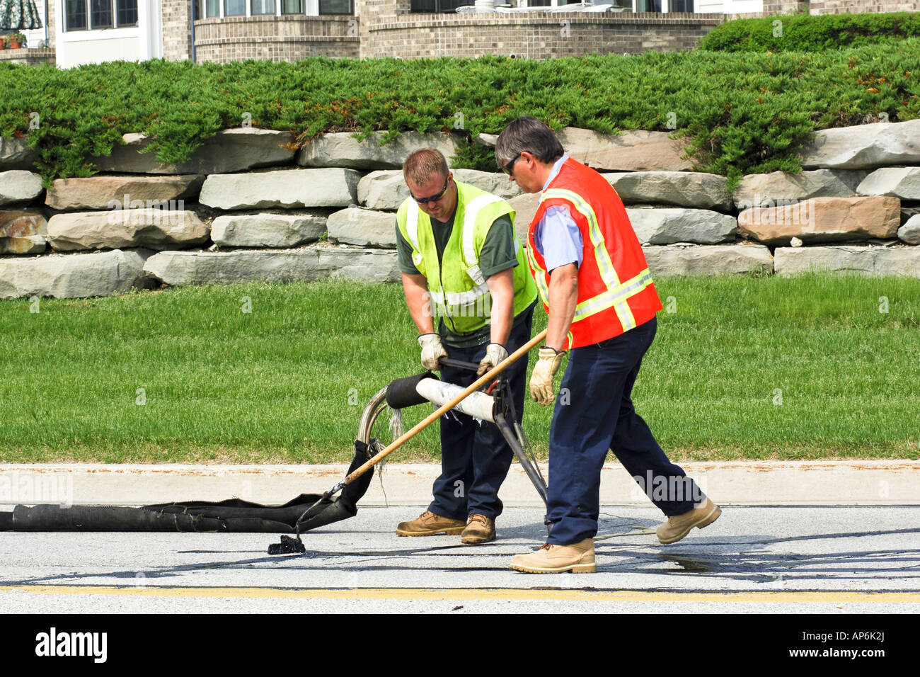 Road maintenance workers tarring in the cracked pavement Stock Photo ...