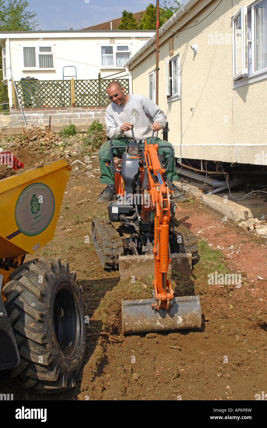 A mini digger excavating soil from a garden Stock Photo - Alamy