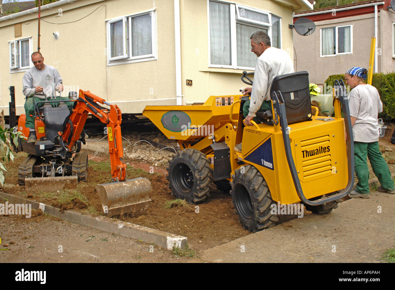 A mini digger dumping soil into a mini dumper truck Stock Photo - Alamy