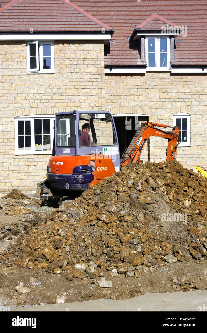 A mini digger being operated at a housing project to dig trenches for ...
