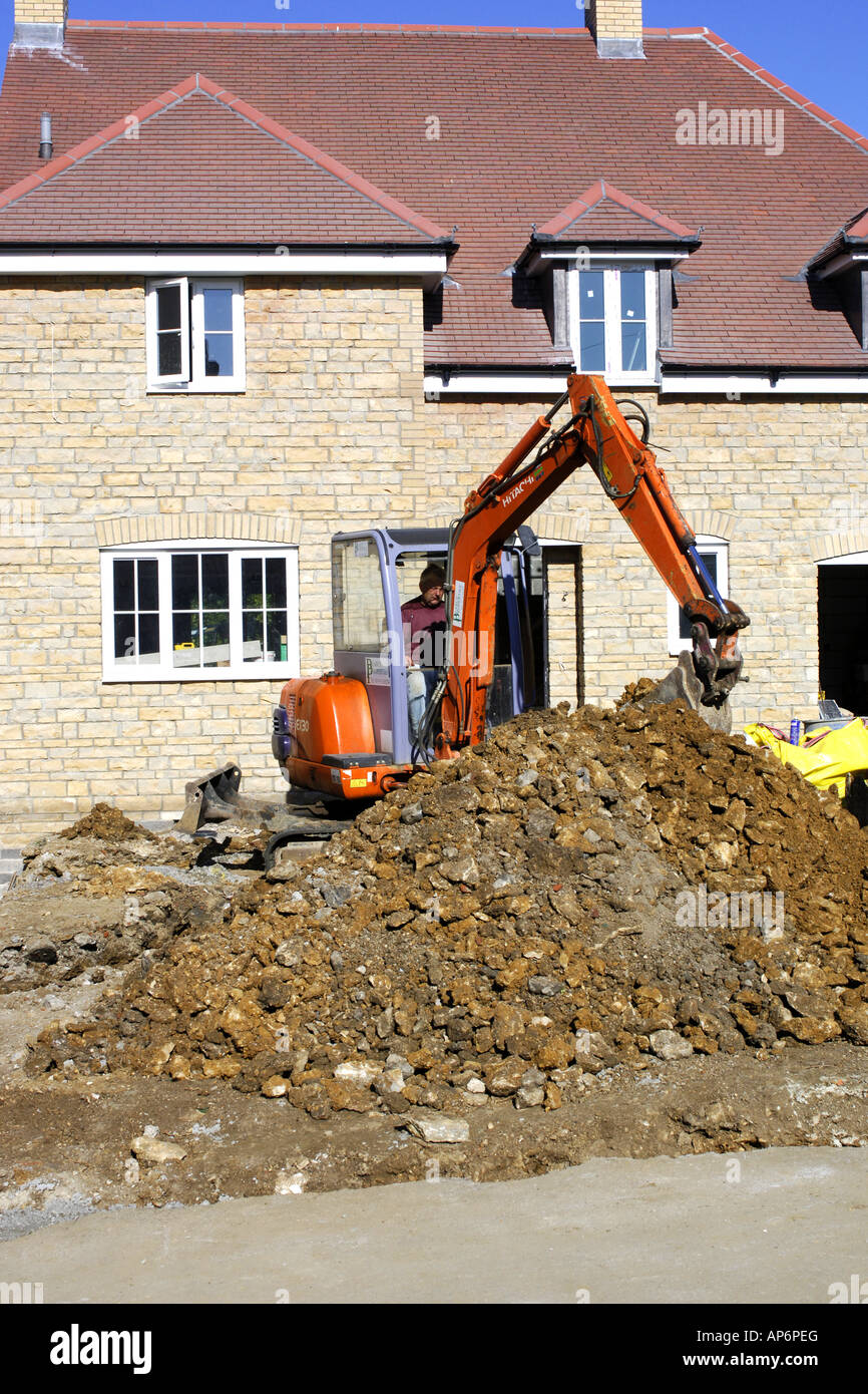 A mini digger being operated at a housing project to dig trenches for ...