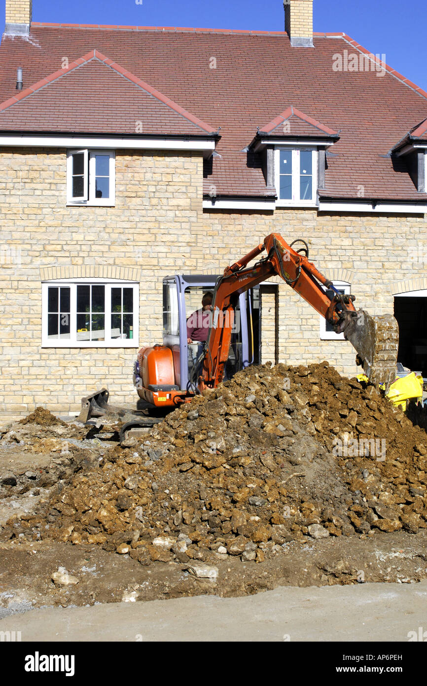 A mini digger being operated at a housing project to dig trenches for ...