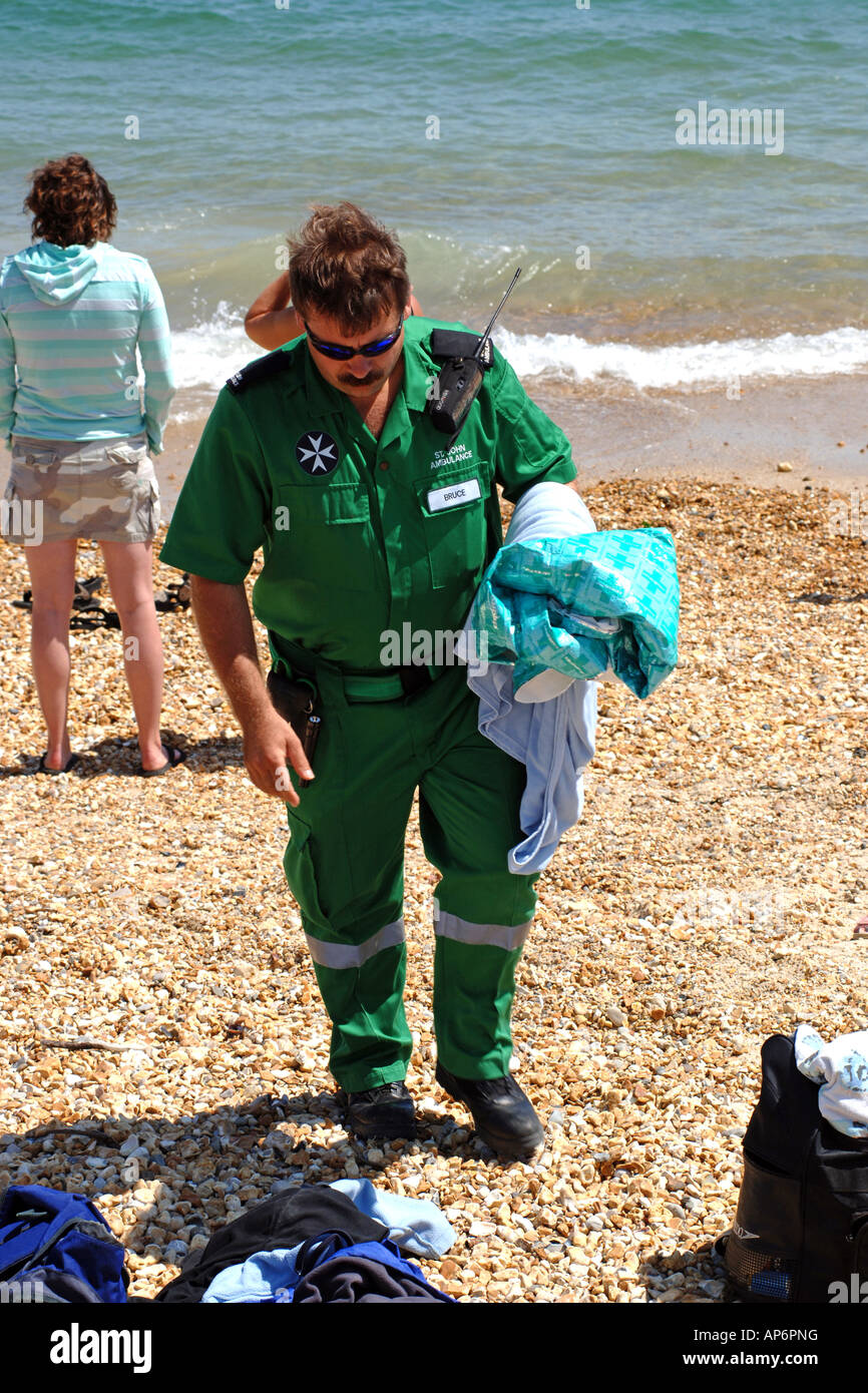 Emergency Paramedic walks up the beach with a blanket in his hand after ...