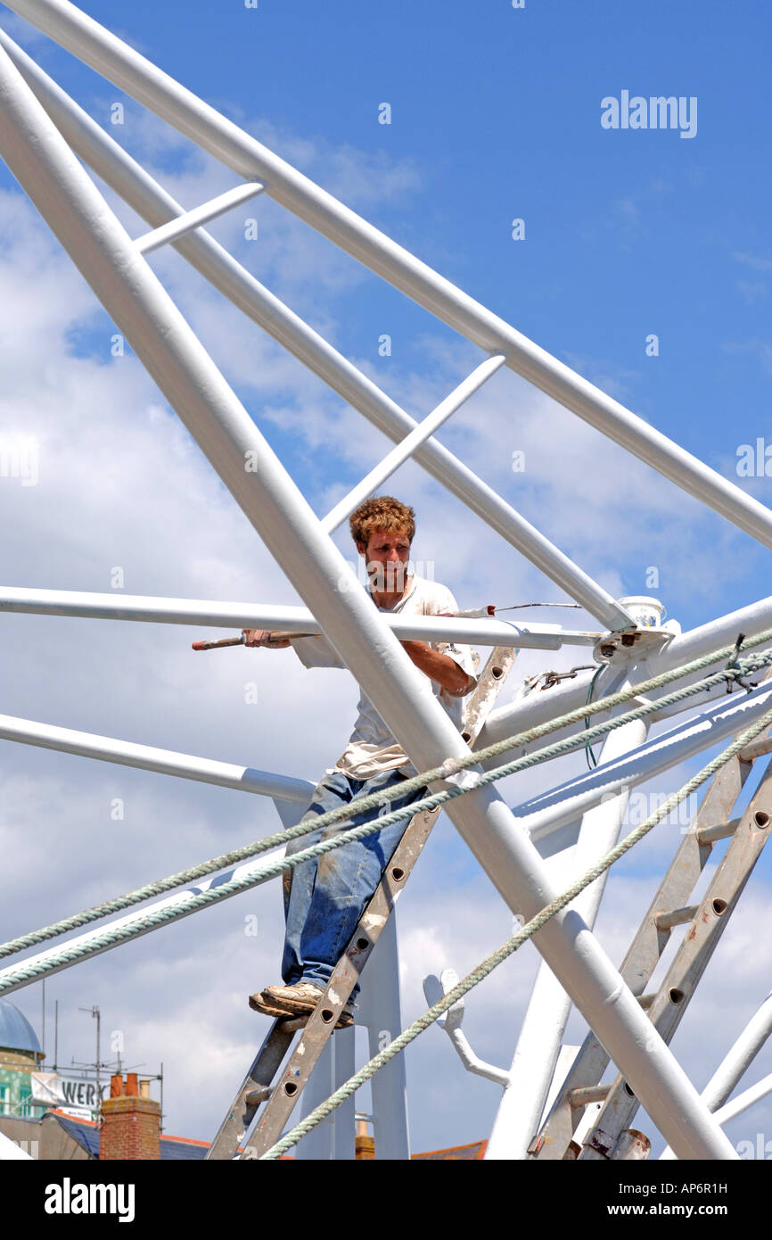 Fishing boat crew member using a long handled paint roller during a ...