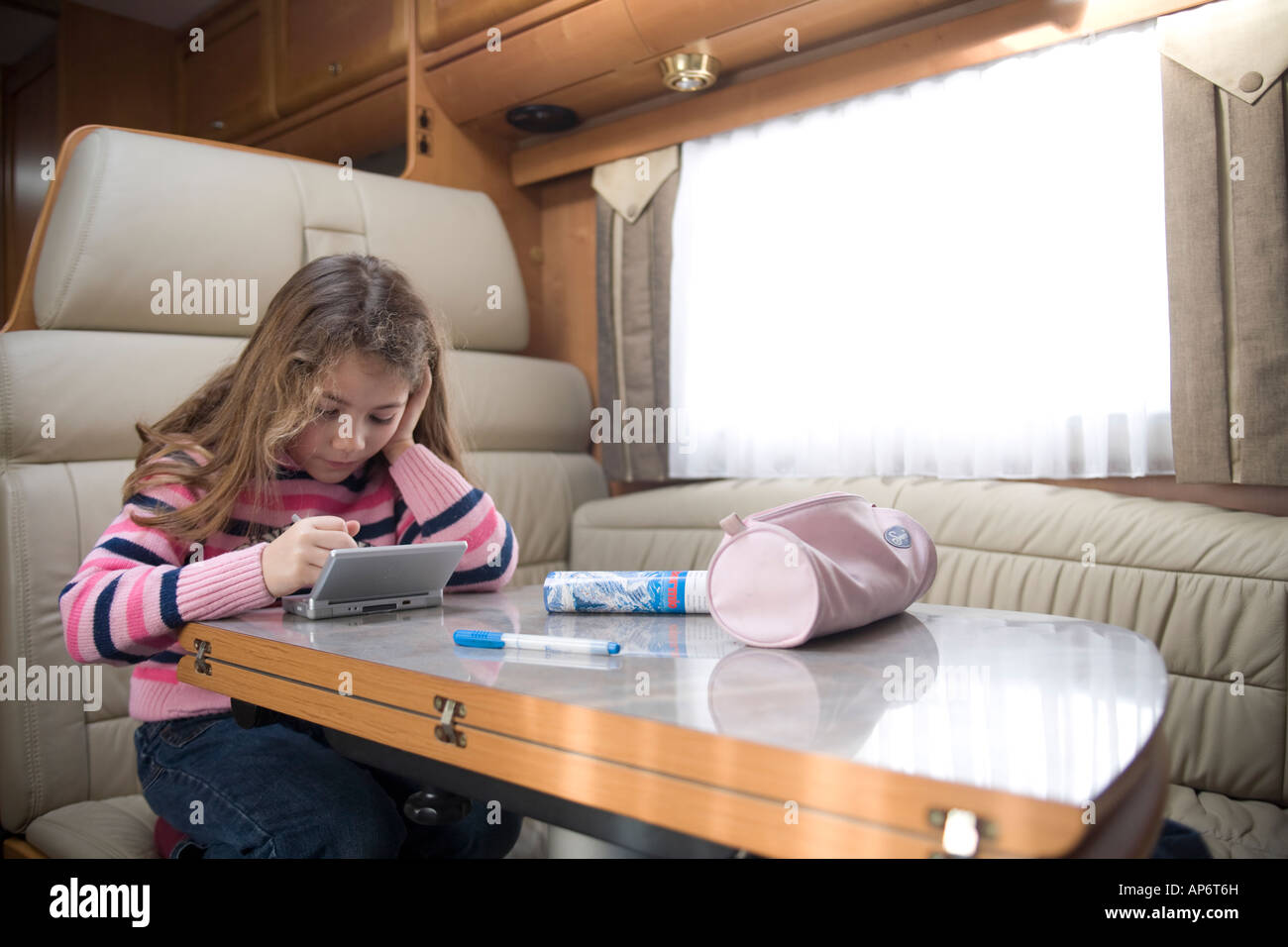 Little girl sitting in a camper van playing with nintendo Ds Stock ...