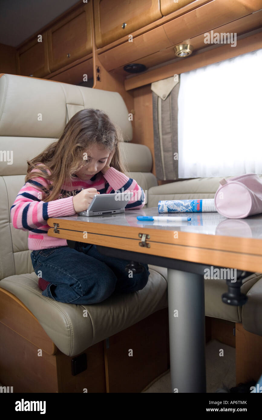 Little girl sitting in a camper van playing with nintendo Ds Stock ...
