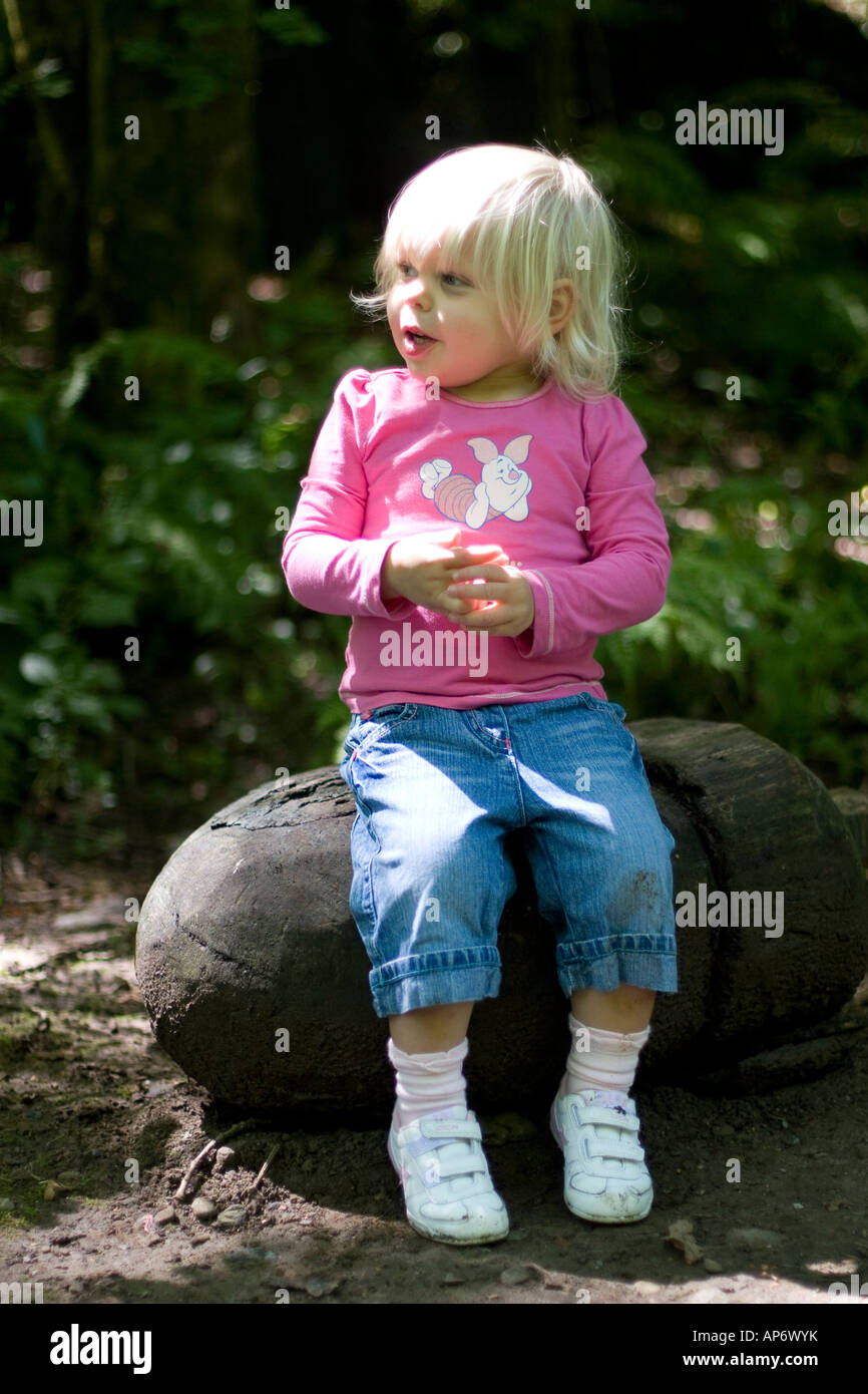 small child sitting on a log Stock Photo - Alamy
