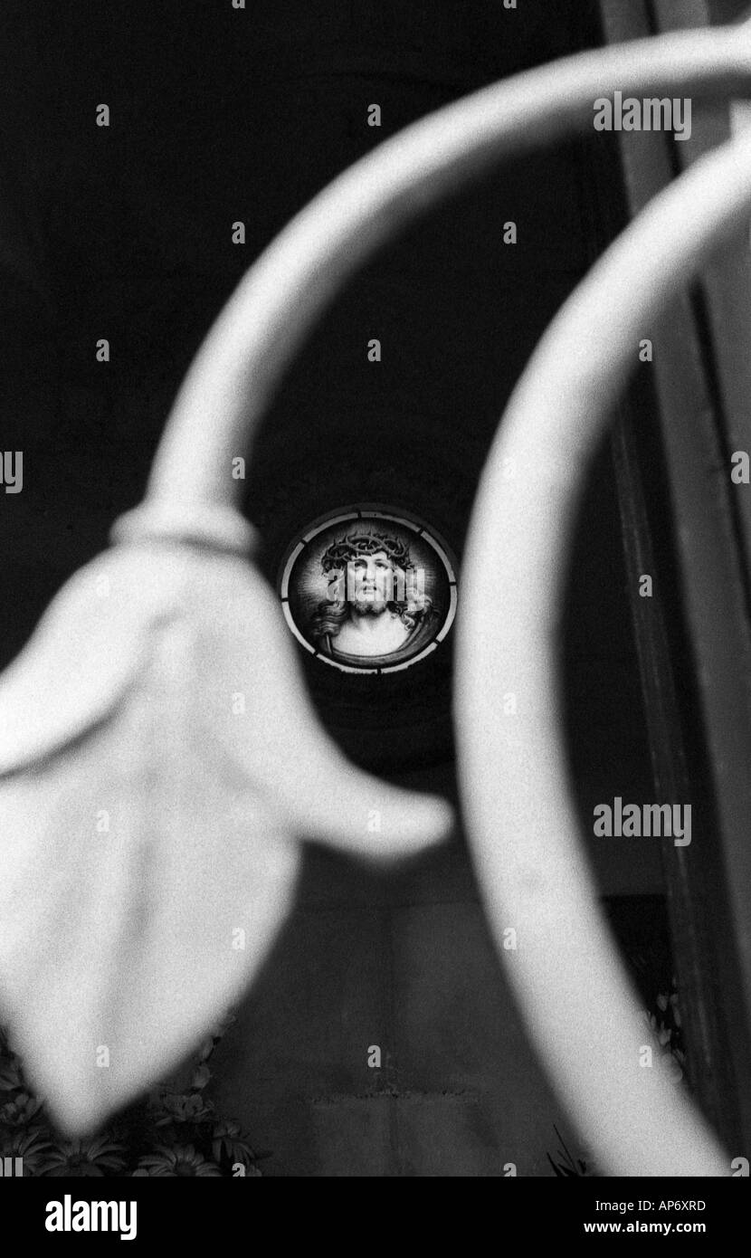 jesus christ on a plaque looking out between the leaves of an iron gate ...