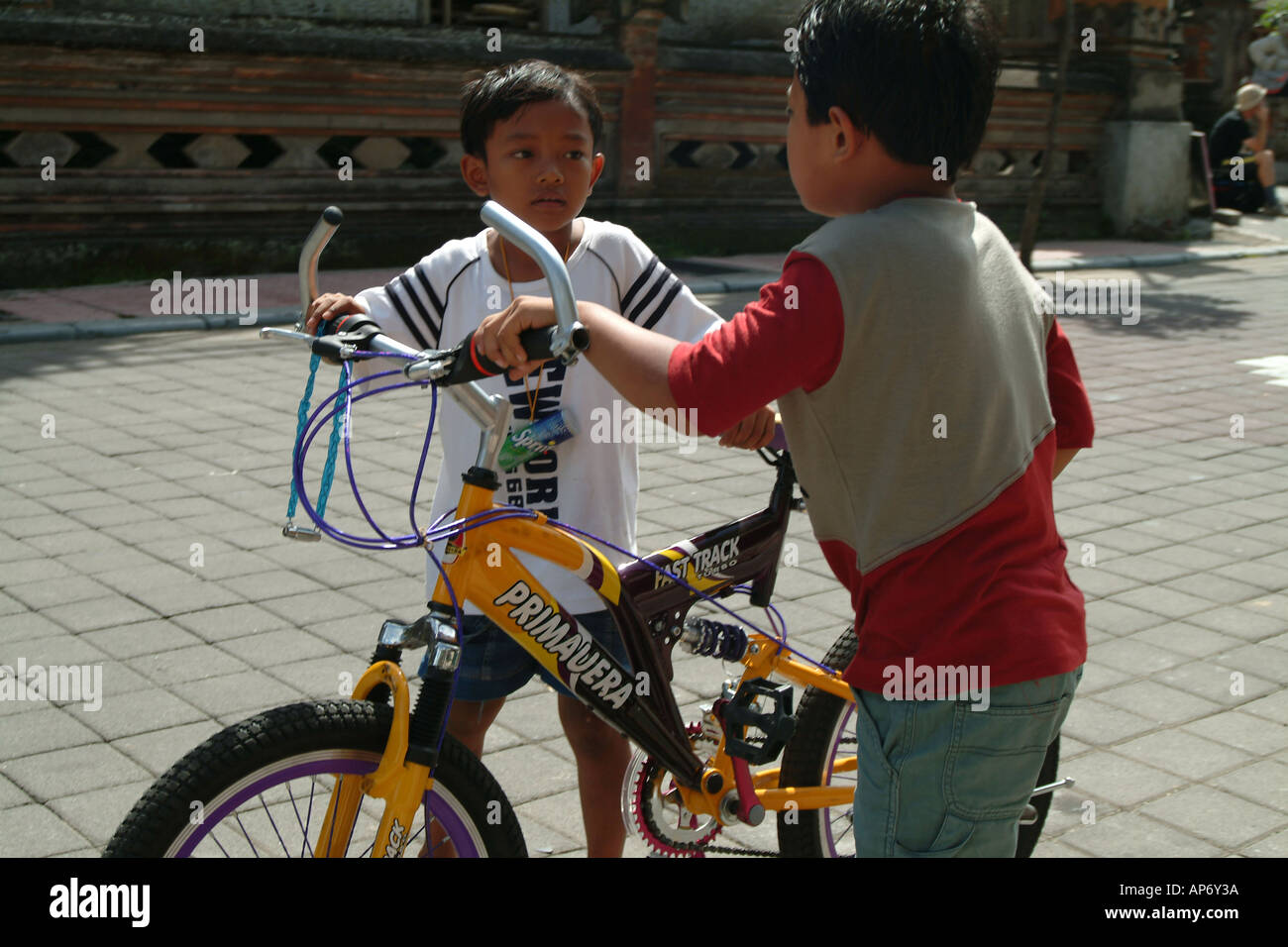 Two kids fight over a bike in ubud Bali Indonesia Stock Photo - Alamy