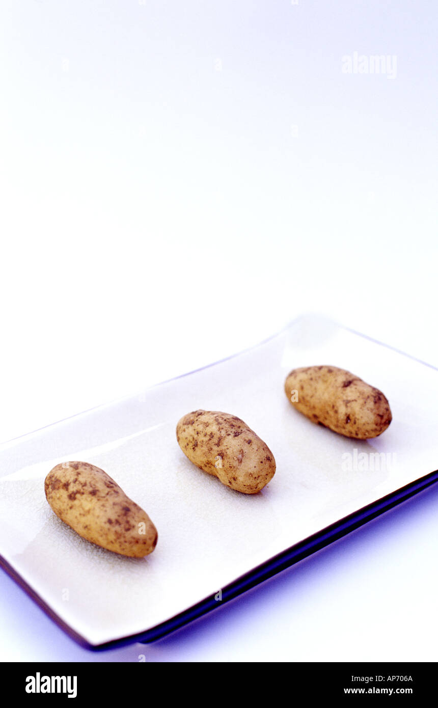 A row of fresh young potatoes lined up on a rectangular plate against ...