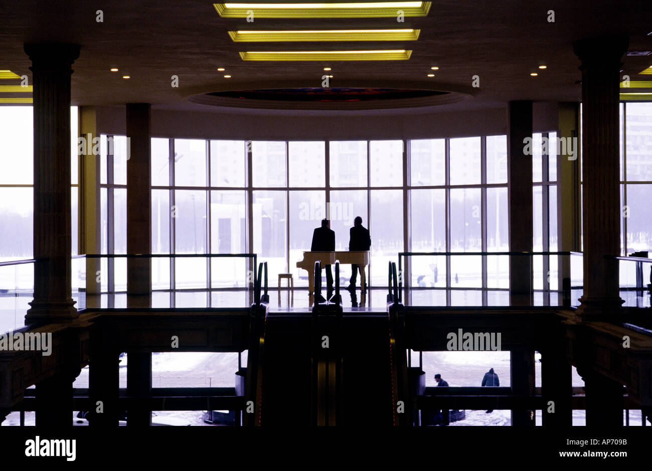 Businessmen in suits stand inside a large office building looing ...