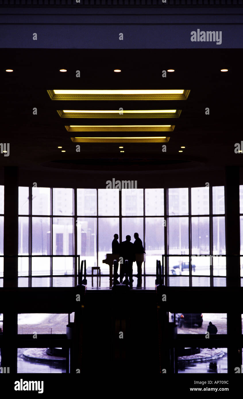 Businessmen in suits stand inside a large office building looking ...