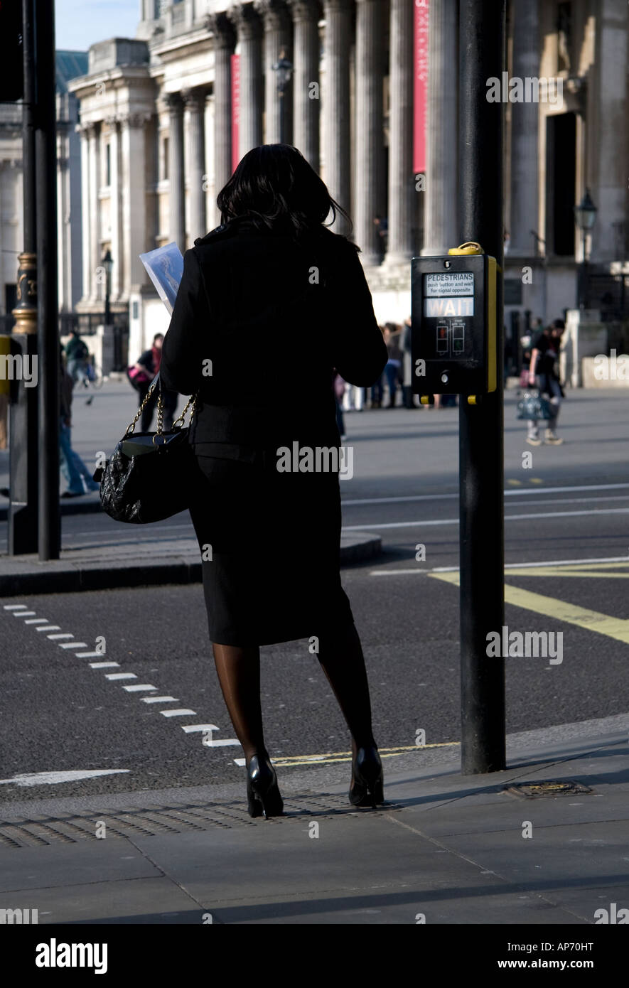 city woman crossing the road at a wait sign while reading paper Stock ...