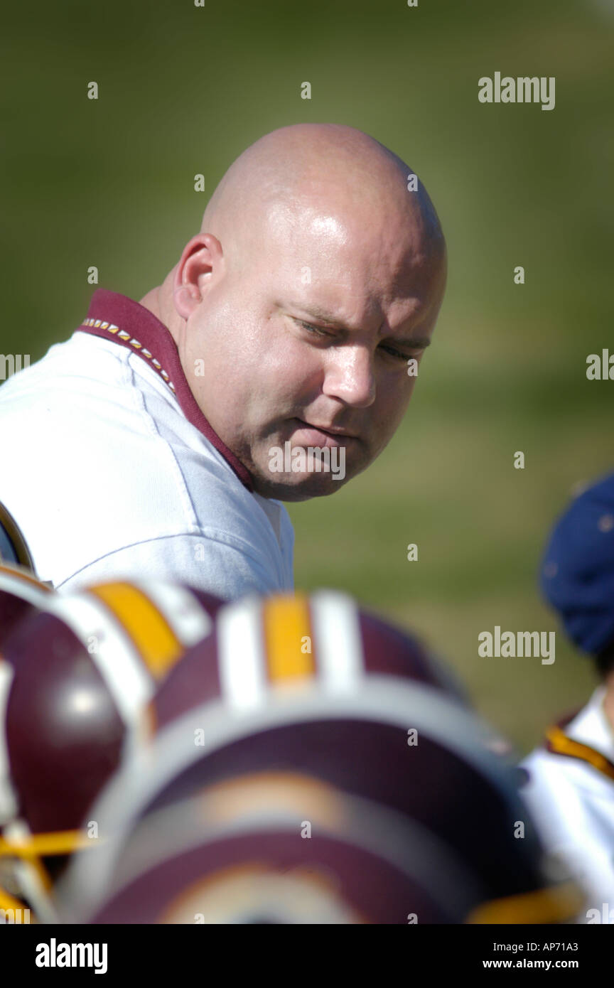 Coach with shaved bald head with young full contact football players ...