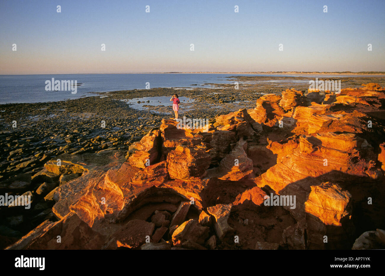A young woman hiker enjoys a view of the startling red rocks near the ...