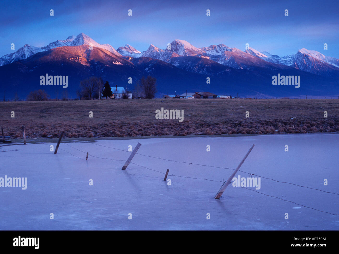 Western Montana ranch farm with snow capped Mission Mountains at sunset ...