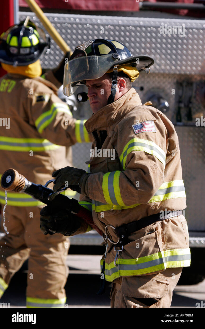 A firefighter holding a fire hose nozzle at an emergency fire scene ...