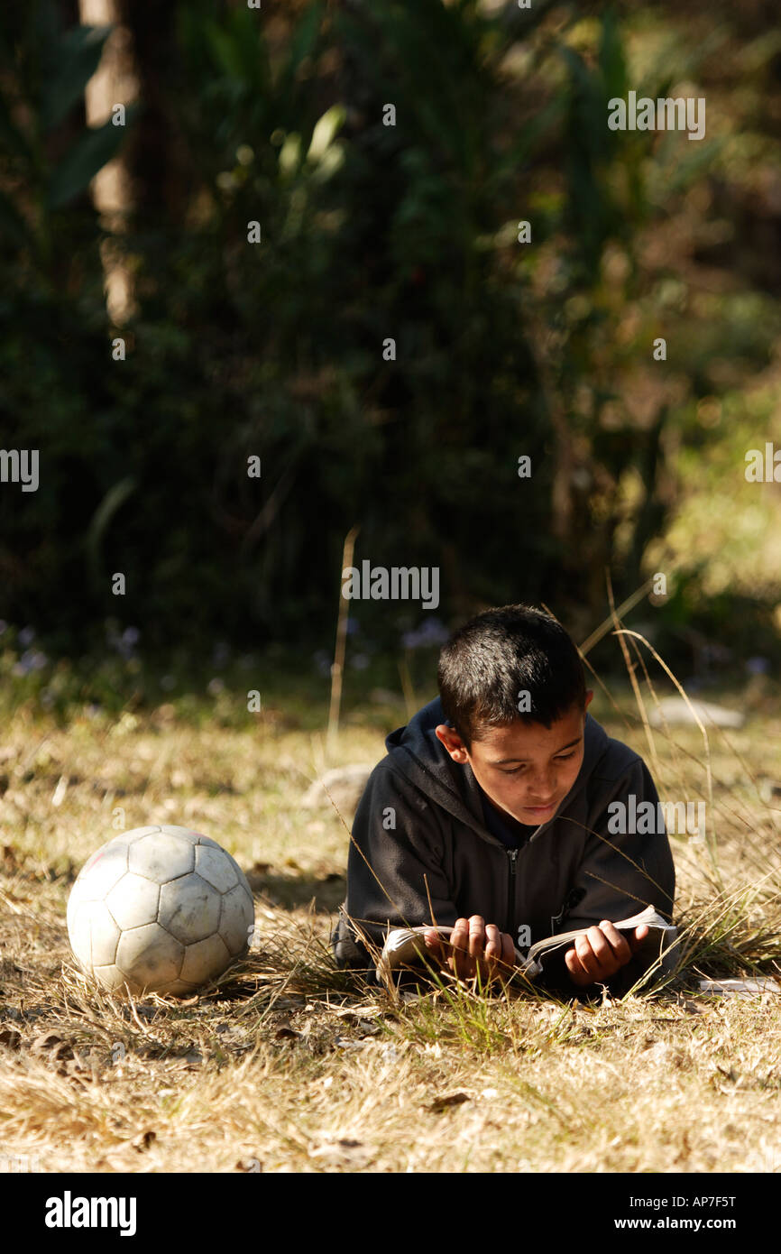 Boy with football reading book Stock Photo - Alamy