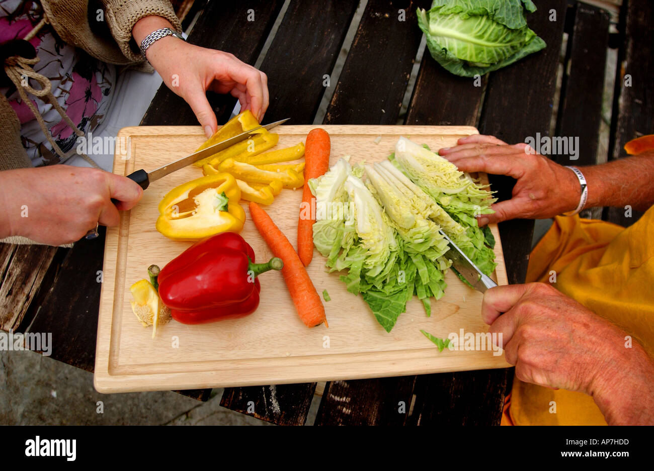 two people cutting and preparing fresh salad and vegetables on a ...