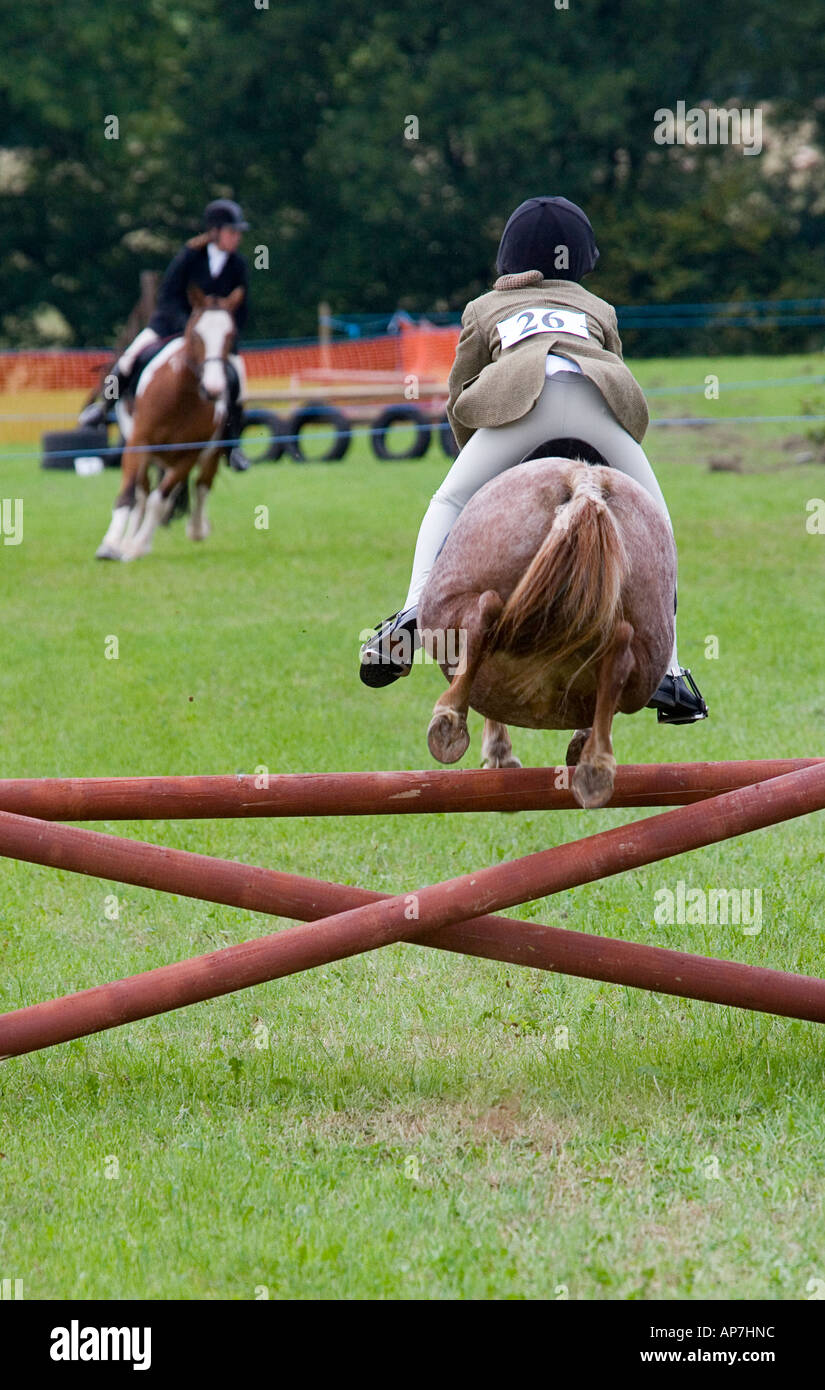 SMALL GIRL ON SMALL HORSE FROM THE REAR IN MID AIR HORSE SHOW UK Stock ...