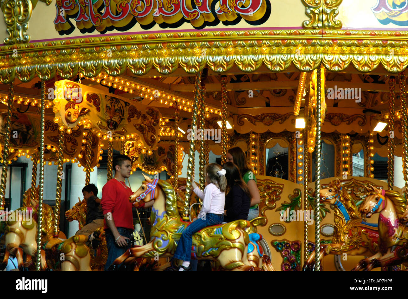 Children with mother on merry go round at fairground Stock Photo - Alamy