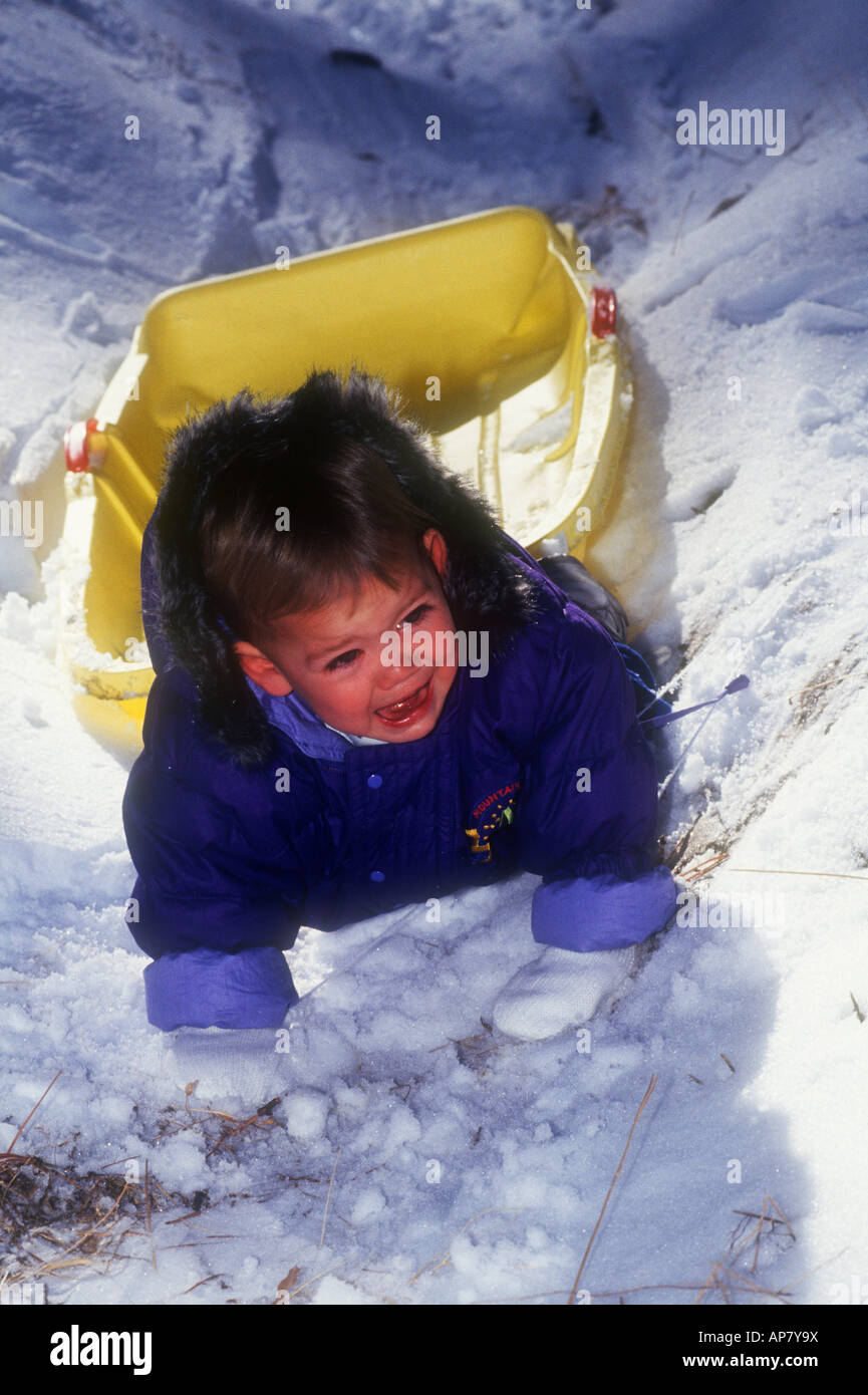 Three year old white boy cries after falling off his sled in the snow ...