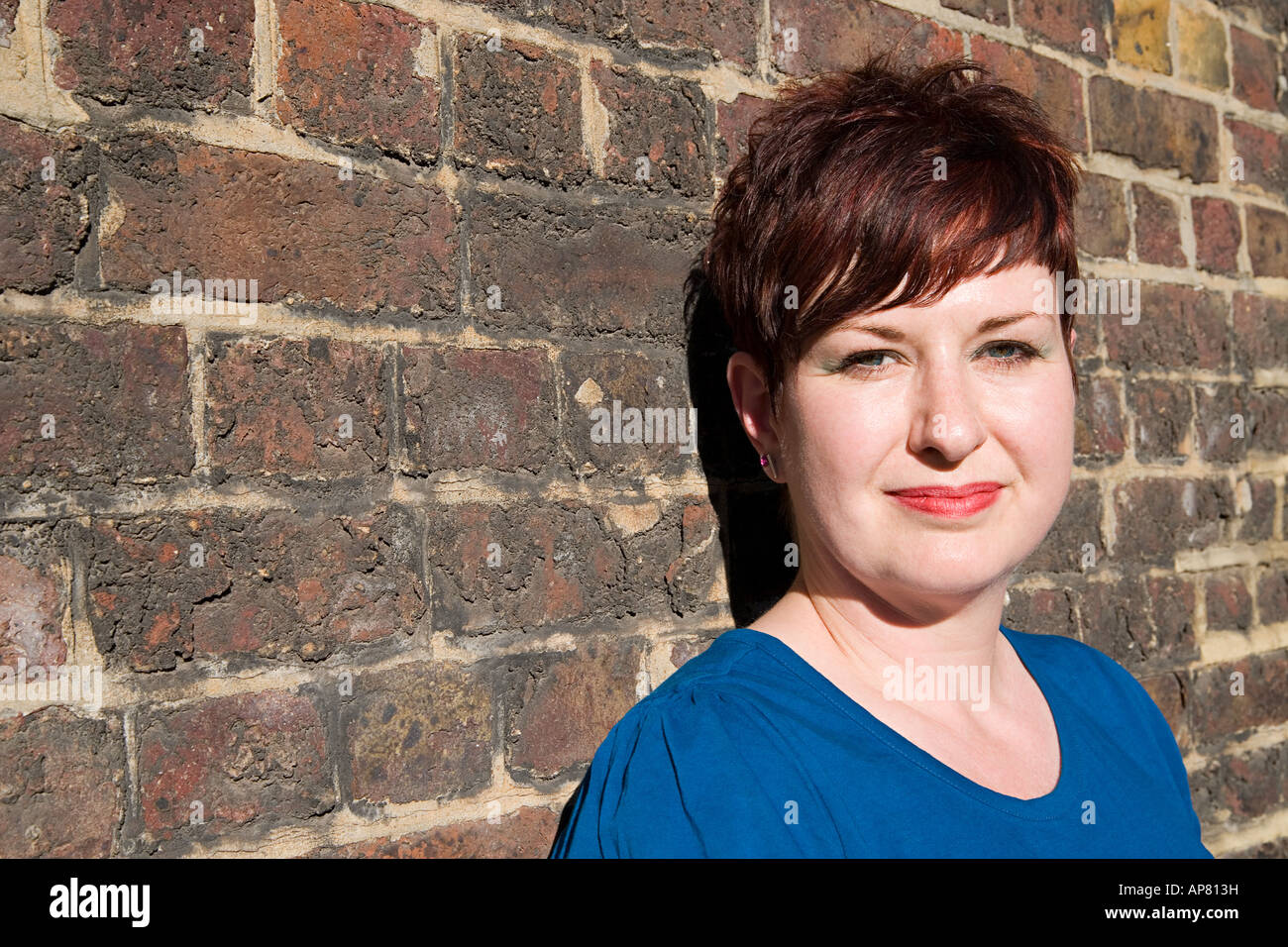 Woman standing against a brick wall Stock Photo - Alamy