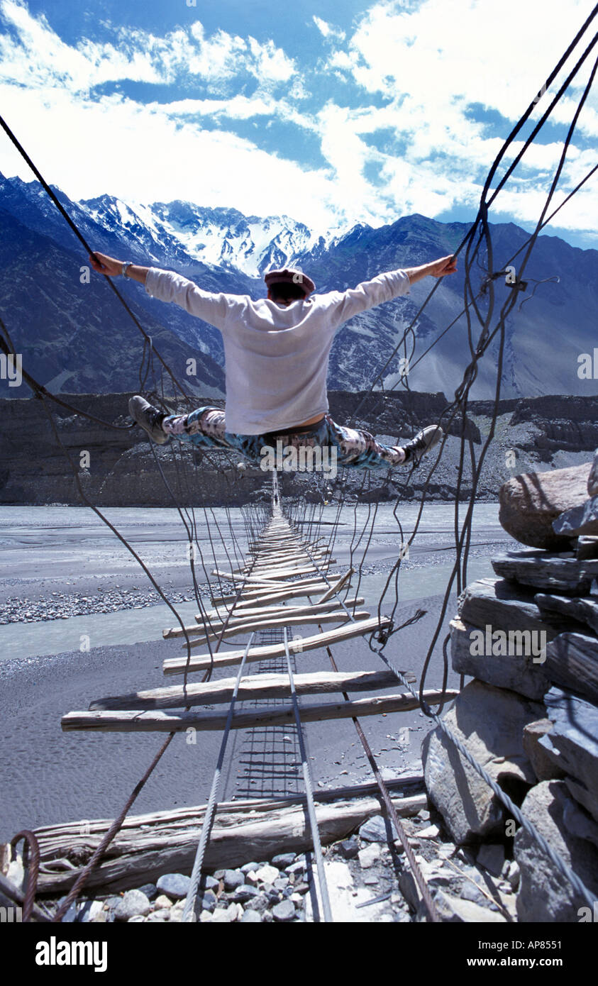 Intrepid traveller crossing the Hunza river on suspended footbridge ...