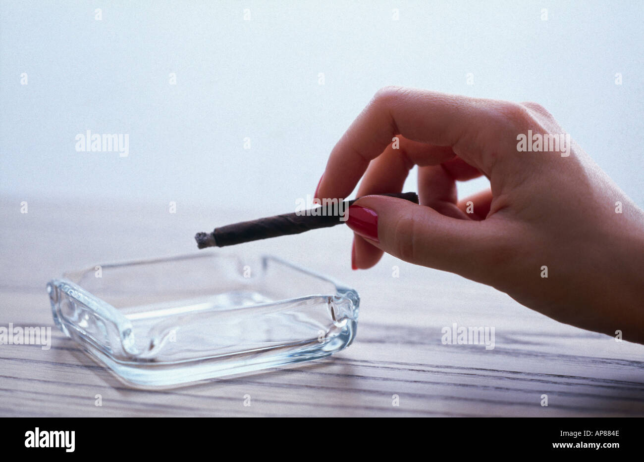 Close-up of woman's hand holding cigar over ashtray Stock Photo - Alamy