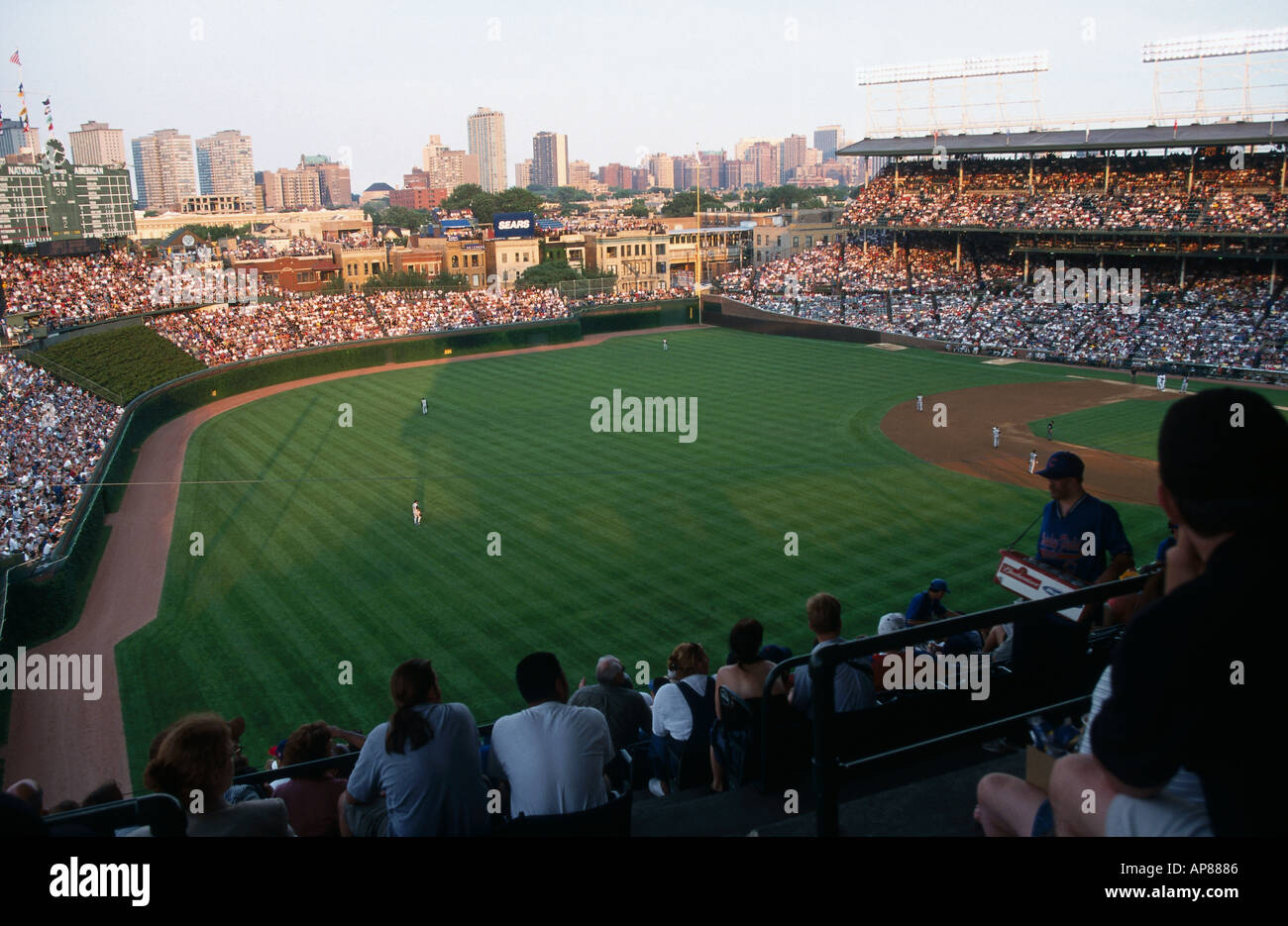 Spectators watching baseball game in stadium with city skyline in ...