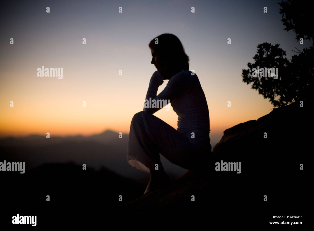 Very colorful sunset with silhouette of woman that can be thinking ...