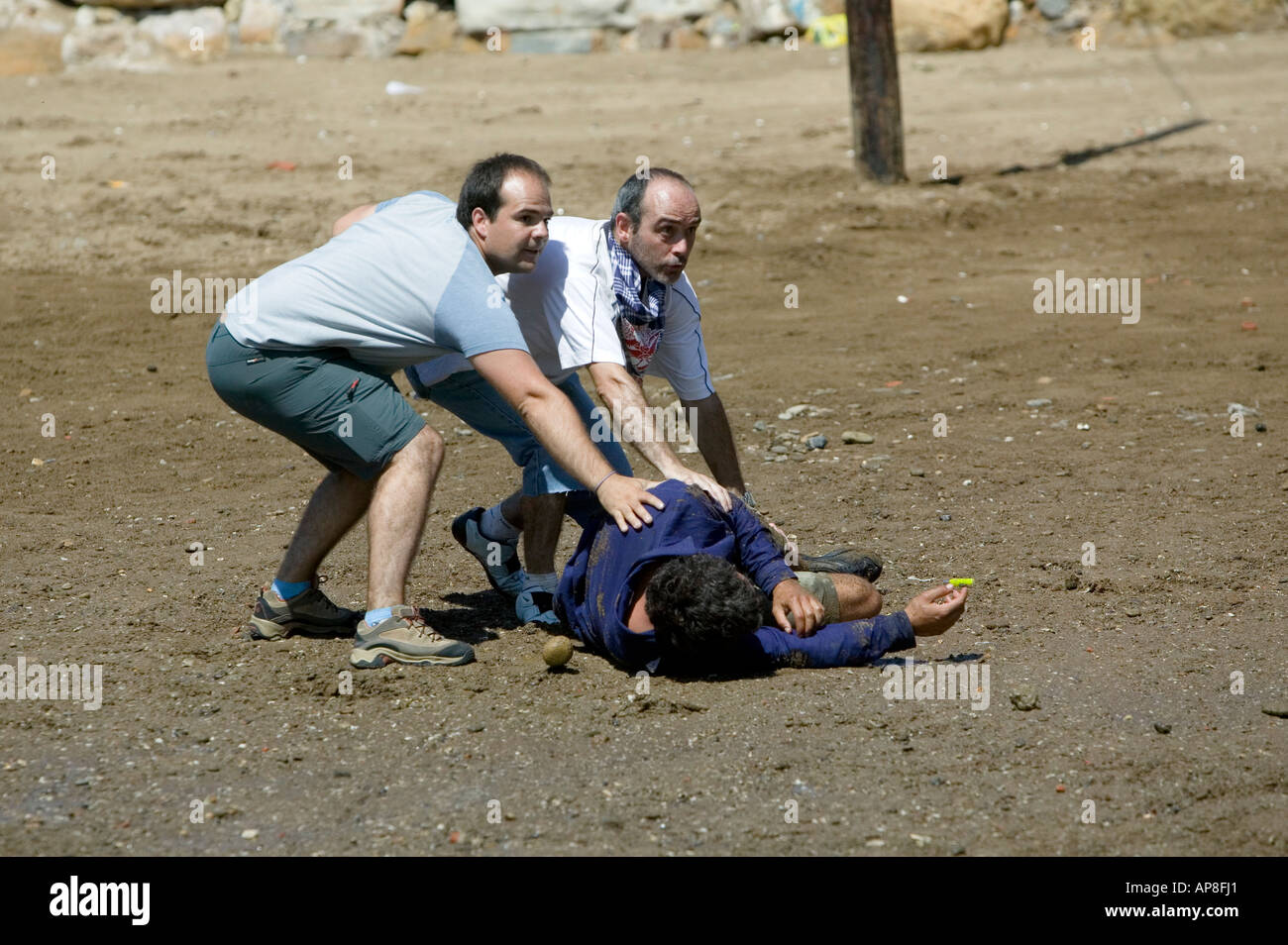 Two men help man on ground while watching out for bull to charge ...
