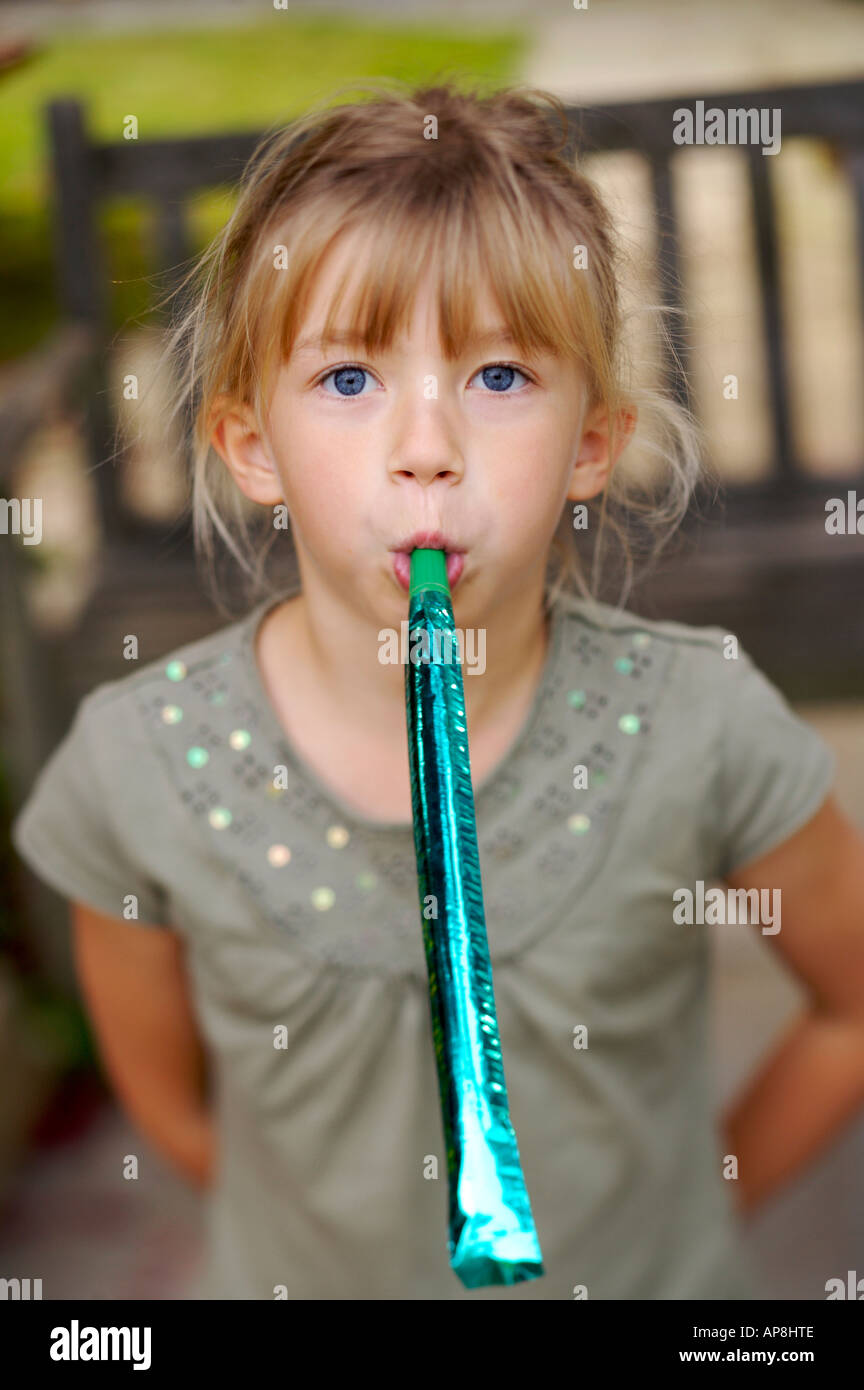 Young girl blowing a party popper Stock Photo - Alamy