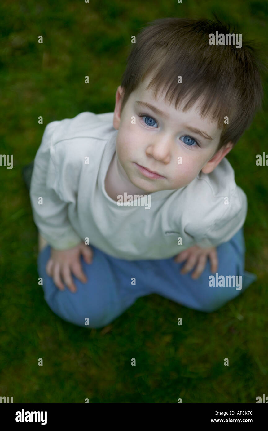 Young boy sitting down looking at camera Stock Photo - Alamy