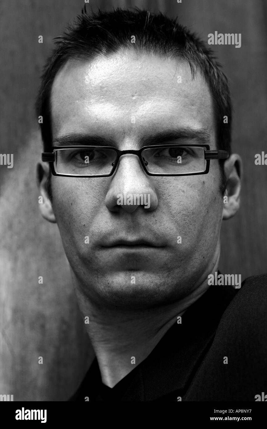 "somber looking male wearing square glasses Stock Photo - Alamy