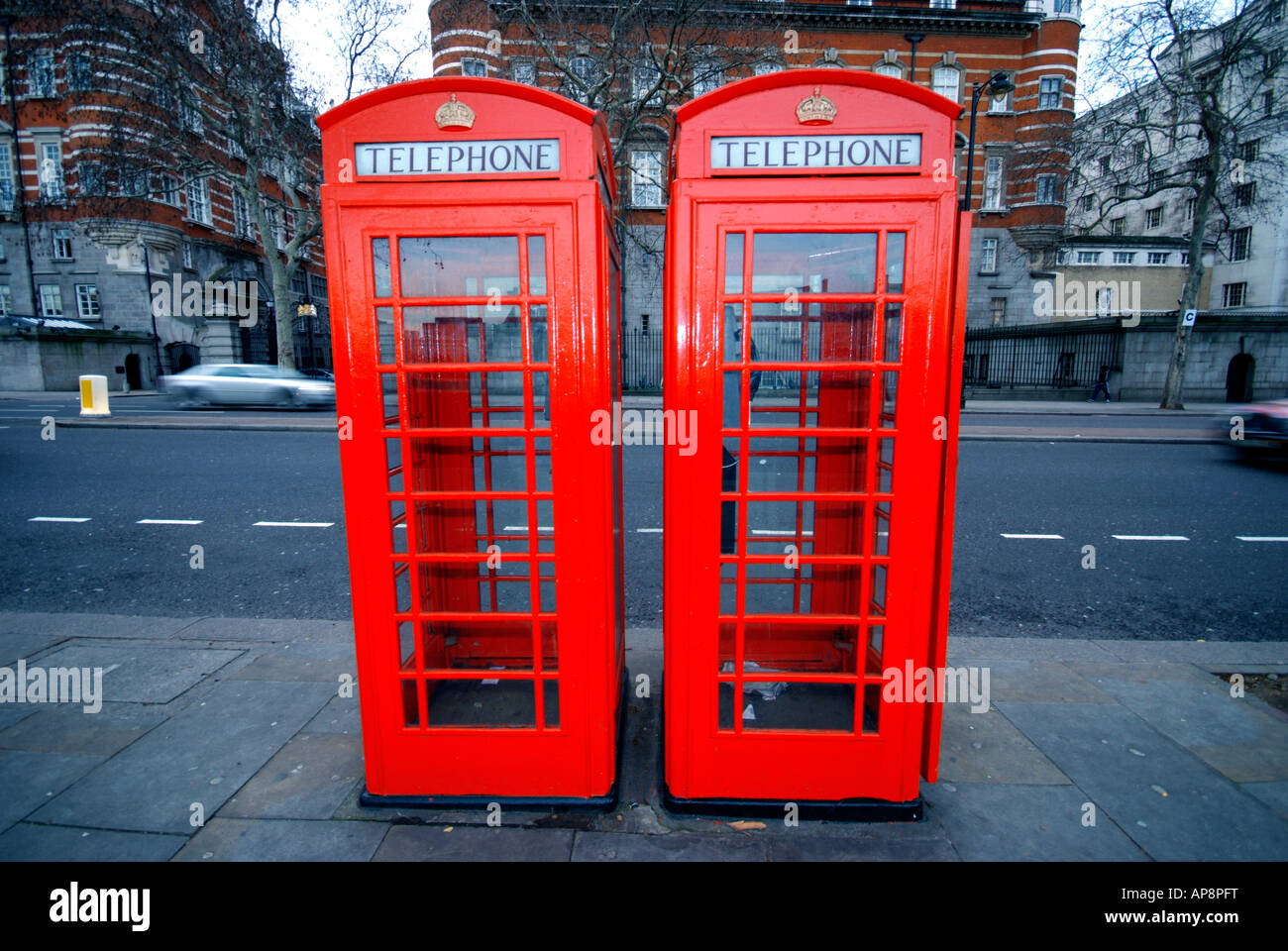 Two red telephone boxes together on the pavement on a London street ...