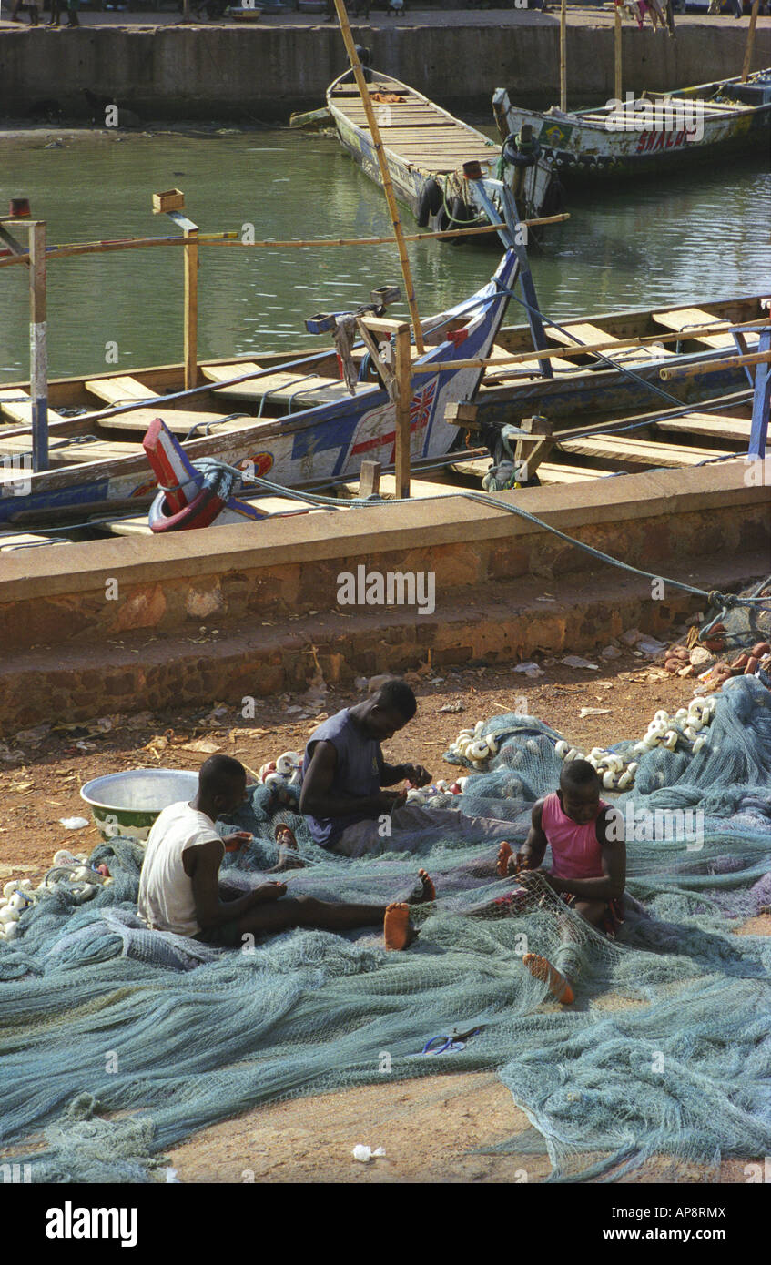Three men mending fishing nets on the beach Cape Coast Central Ashanti ...