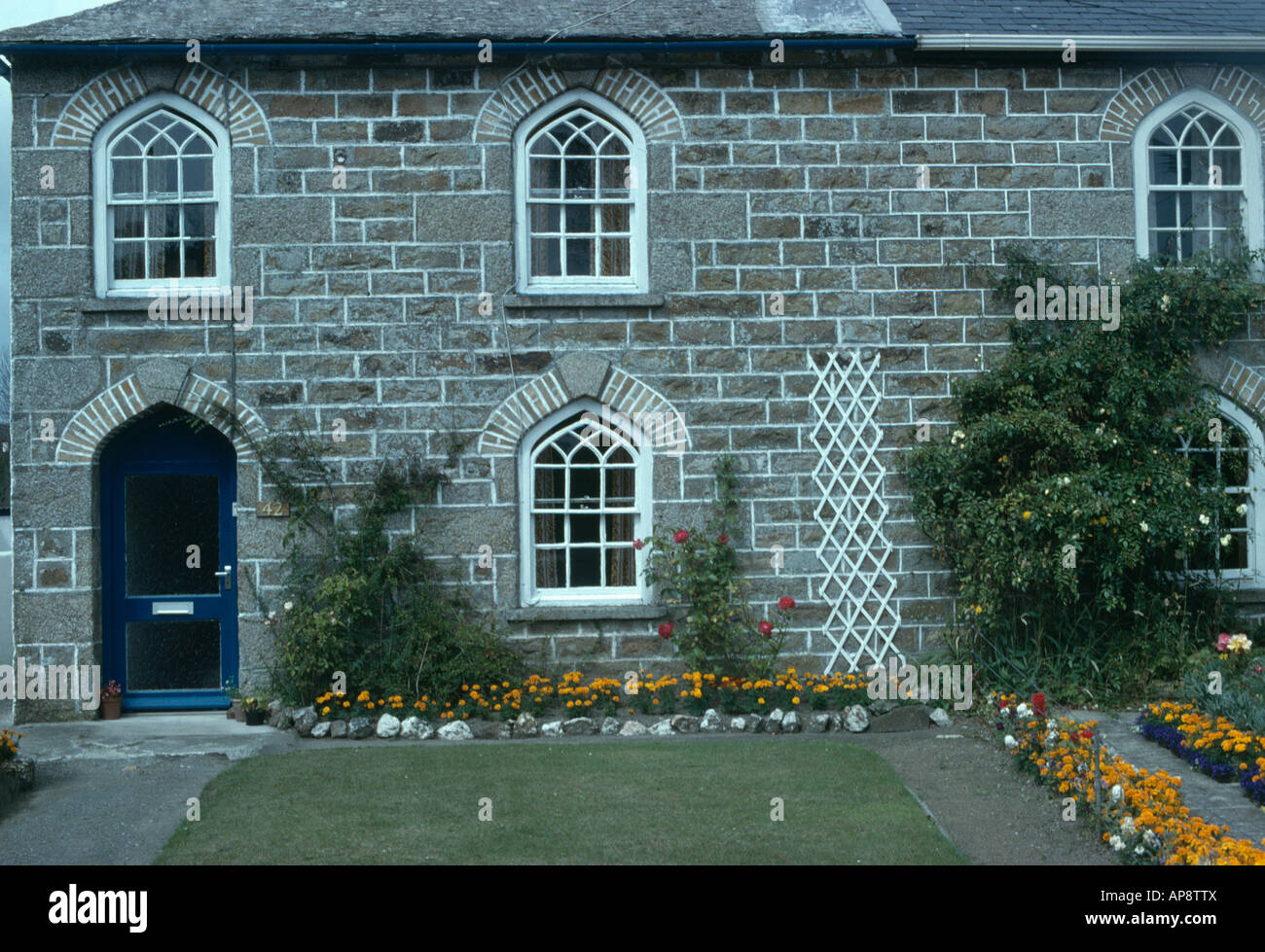 Gothic windows in terraced stone cottage with small front garden Stock ...
