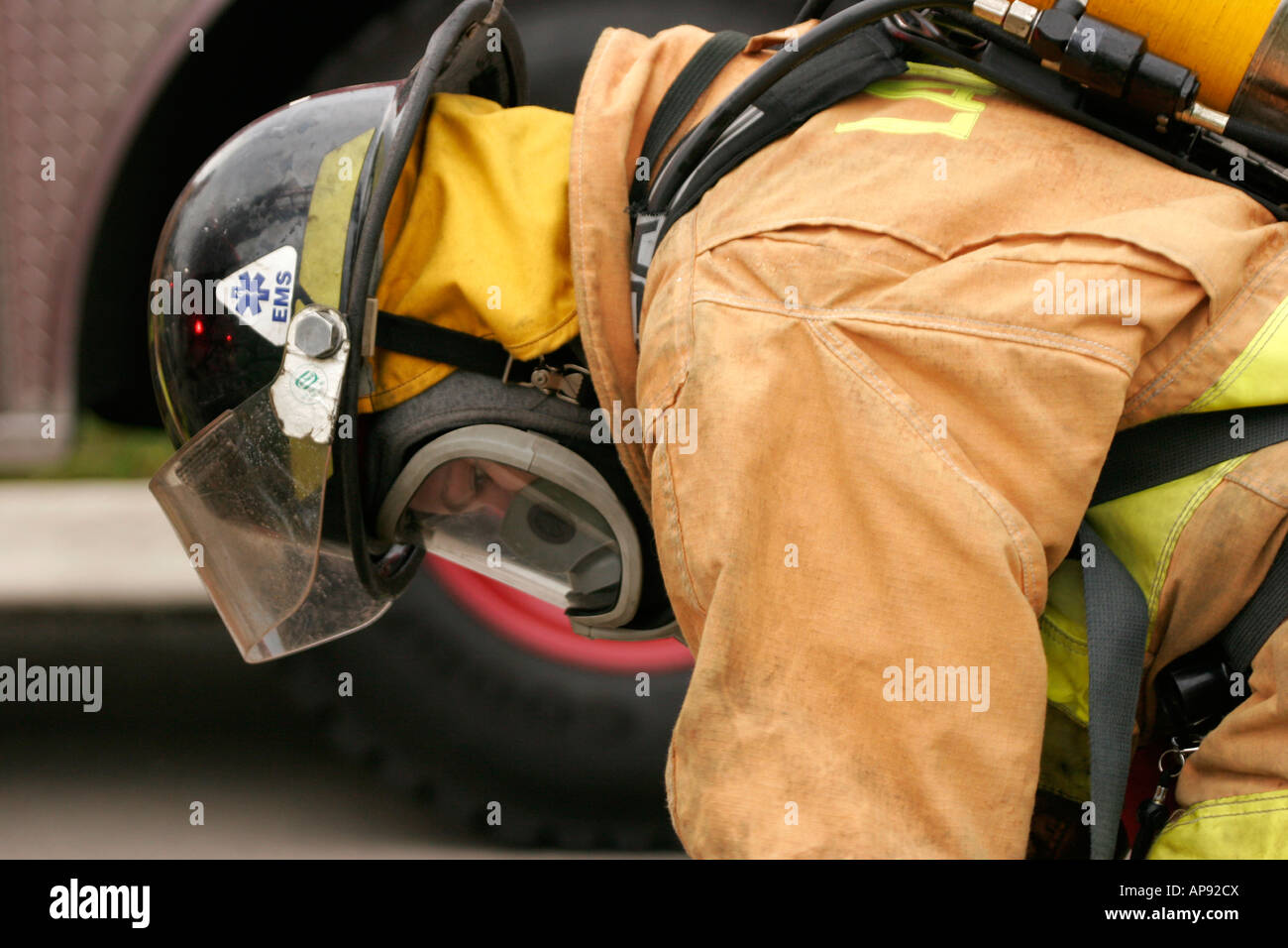 A female firewoman or firefighter bending over picking up equipment at ...