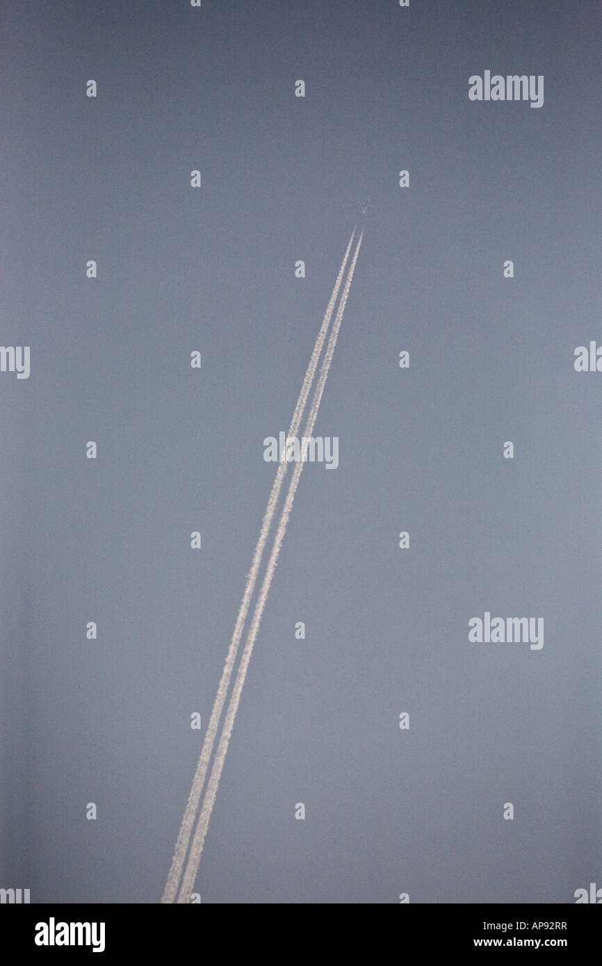 A jet aircraft climbs ever upward on a grey morning sky, leaving two ...