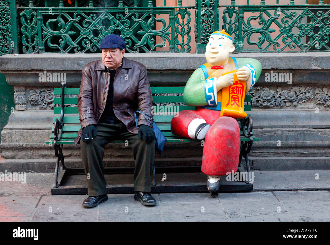 Local Chinese adult male sitting next to statue of traditional Chinese ...
