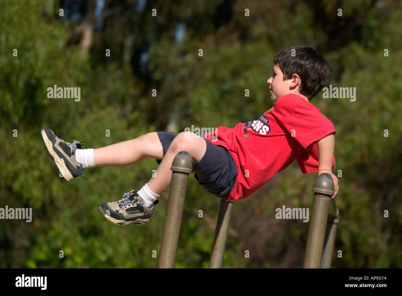 A daring young boy showing off on a climbing structure at a playground ...