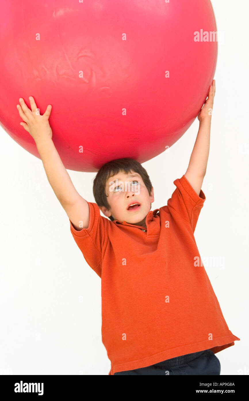 A young boy balances a huge red ball on his head Stock Photo - Alamy