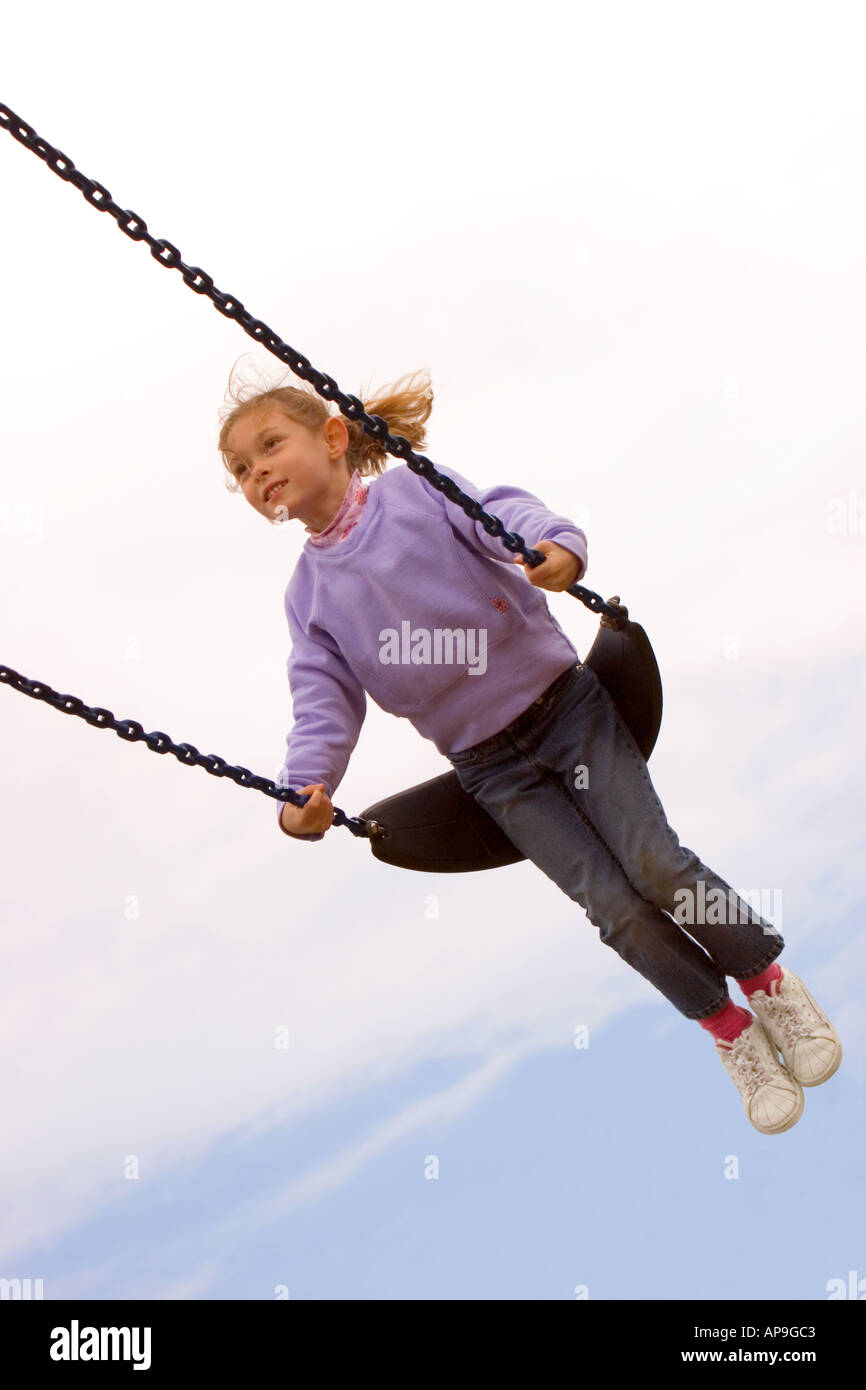 A young girl enjoys swinging high in the sky at a playground Stock ...