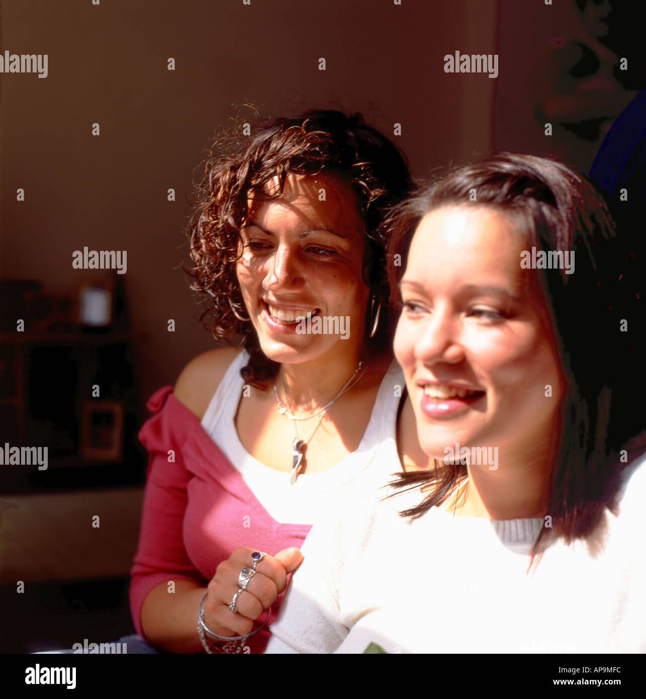 Two young women friends having fun together smiling laughing bathed in ...