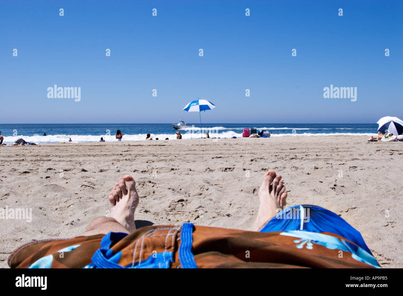 Man lying on the beach watching people Stock Photo - Alamy