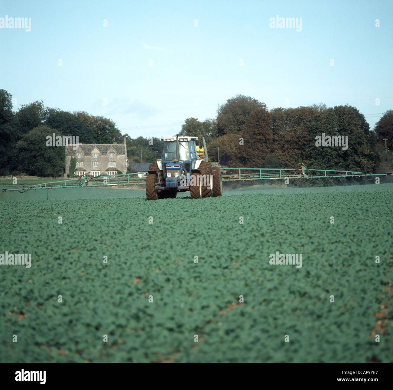 Ford tractor and boom sprayer spraying young oilseed rape crop with a ...