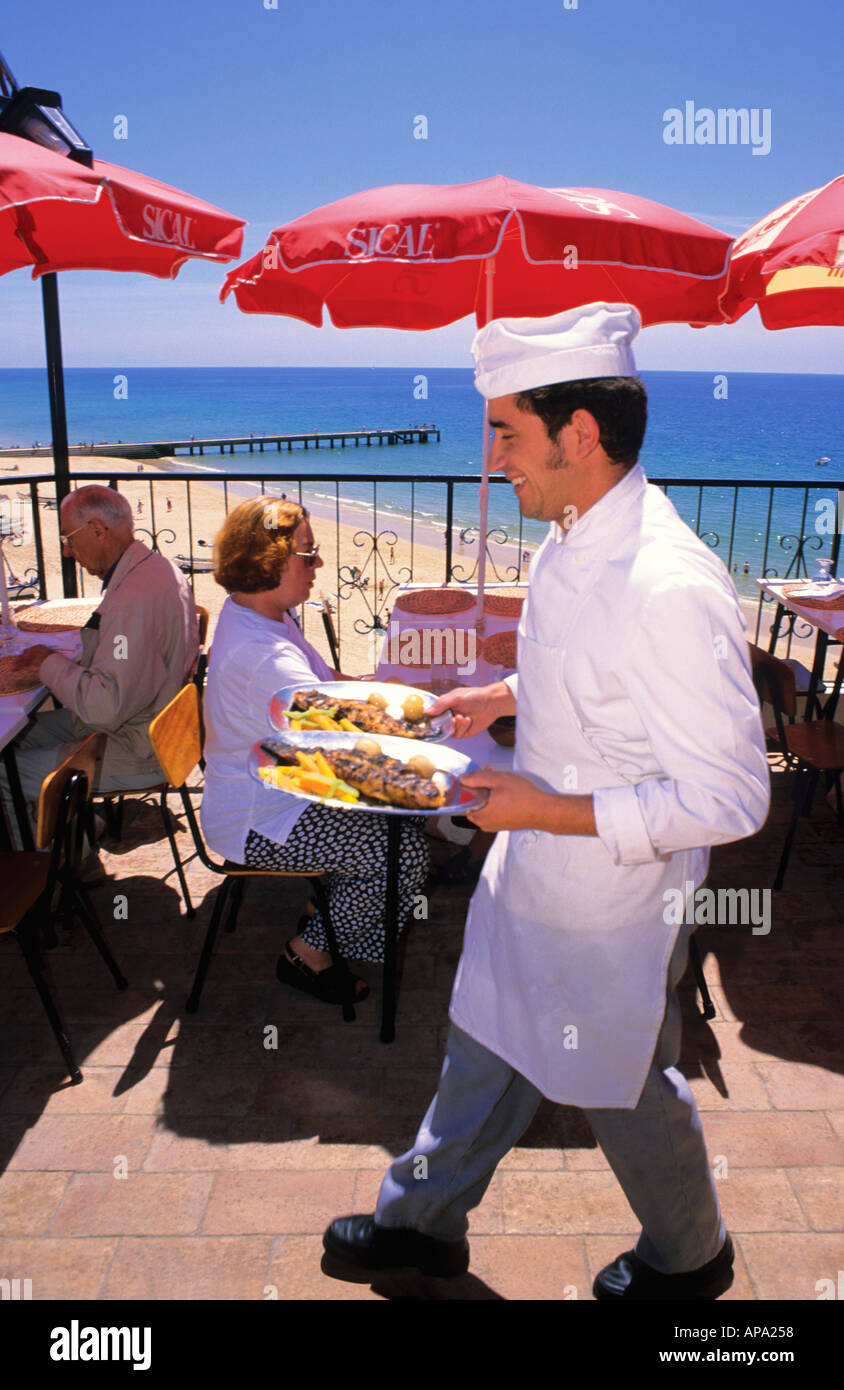 Portugal, Algarve: Waiter serving grilled fish in restaurant Ruinas in ...